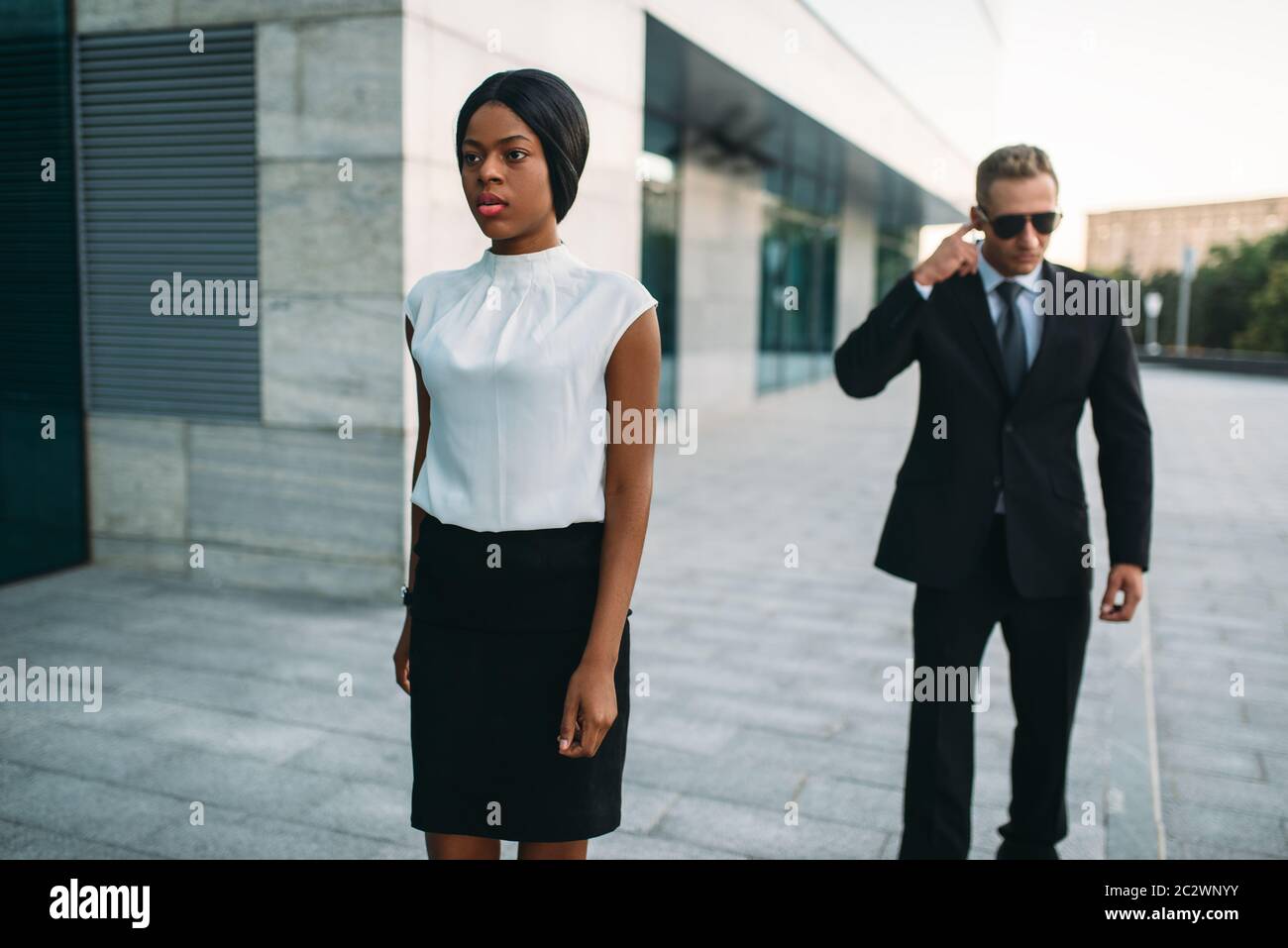 Personal bodyguard in sunglasses and black business woman. Security ...