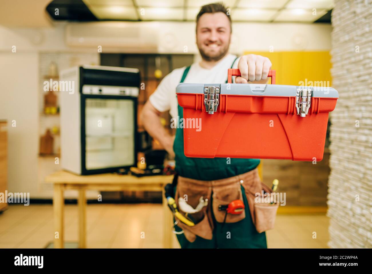Repairman in uniform holds toolbox, handyman. Professional worker makes ...