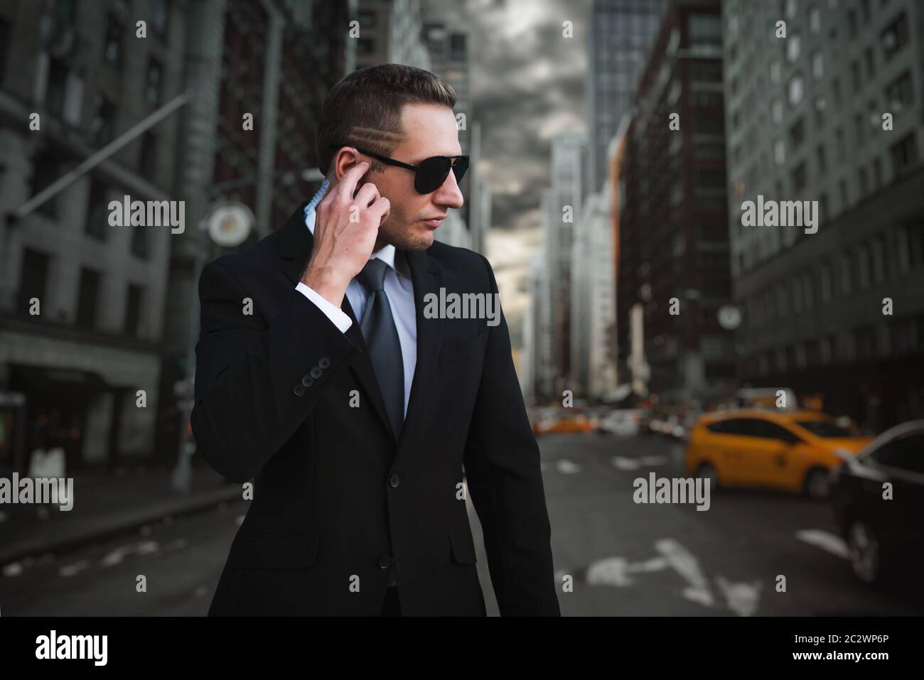 Male bodyguard in suit and sunglasses talking by security earpiece ...