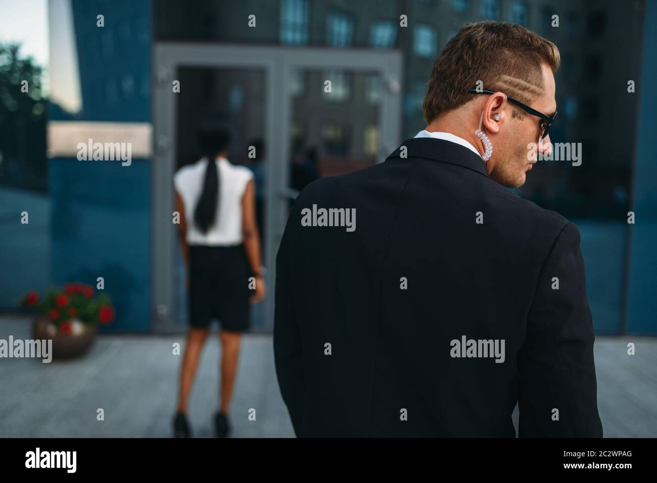 Personal guard in sunglasses and security earpiece, back view, black ...