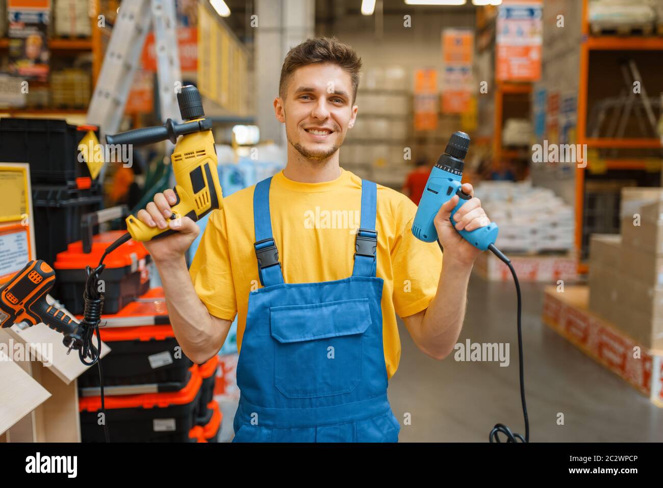 Male builder with power tools in hardware store. Constructor in uniform ...