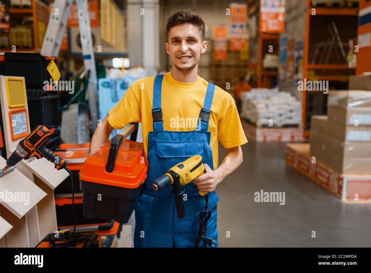 Male constructor holds tools in hardware store. Builder in uniform look ...