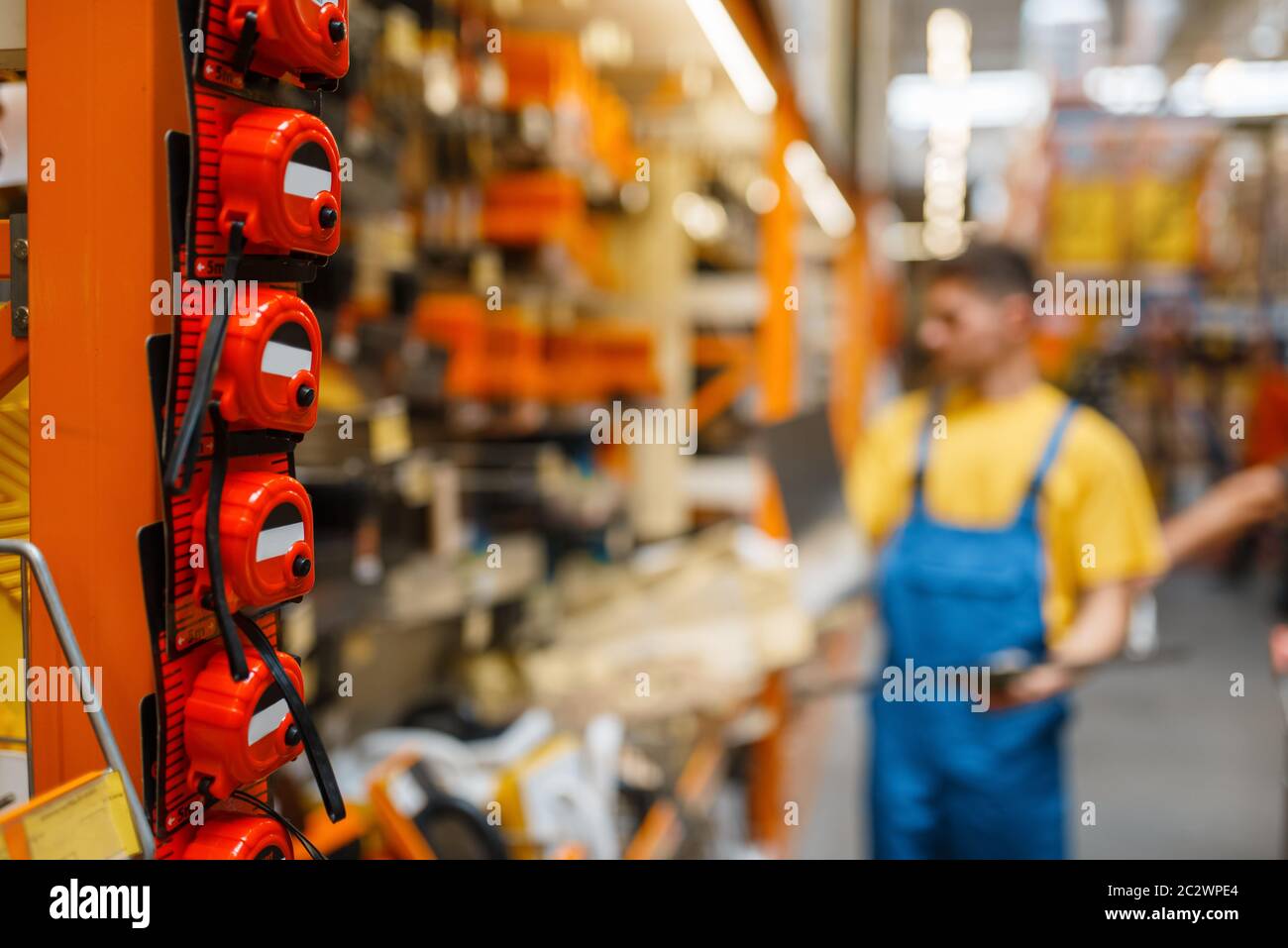 Male builder at the shelf with tools in hardware store. Constructor in ...