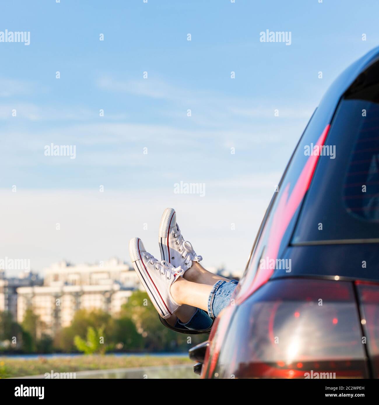 Feet outside the window, cityscape on background. Woman driver put feet ...