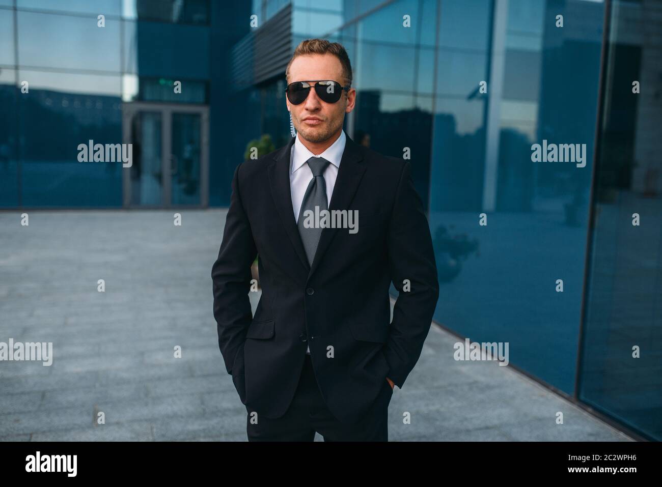 Male bodyguard in suit and sunglasses outdoors. Guarding is a risky ...