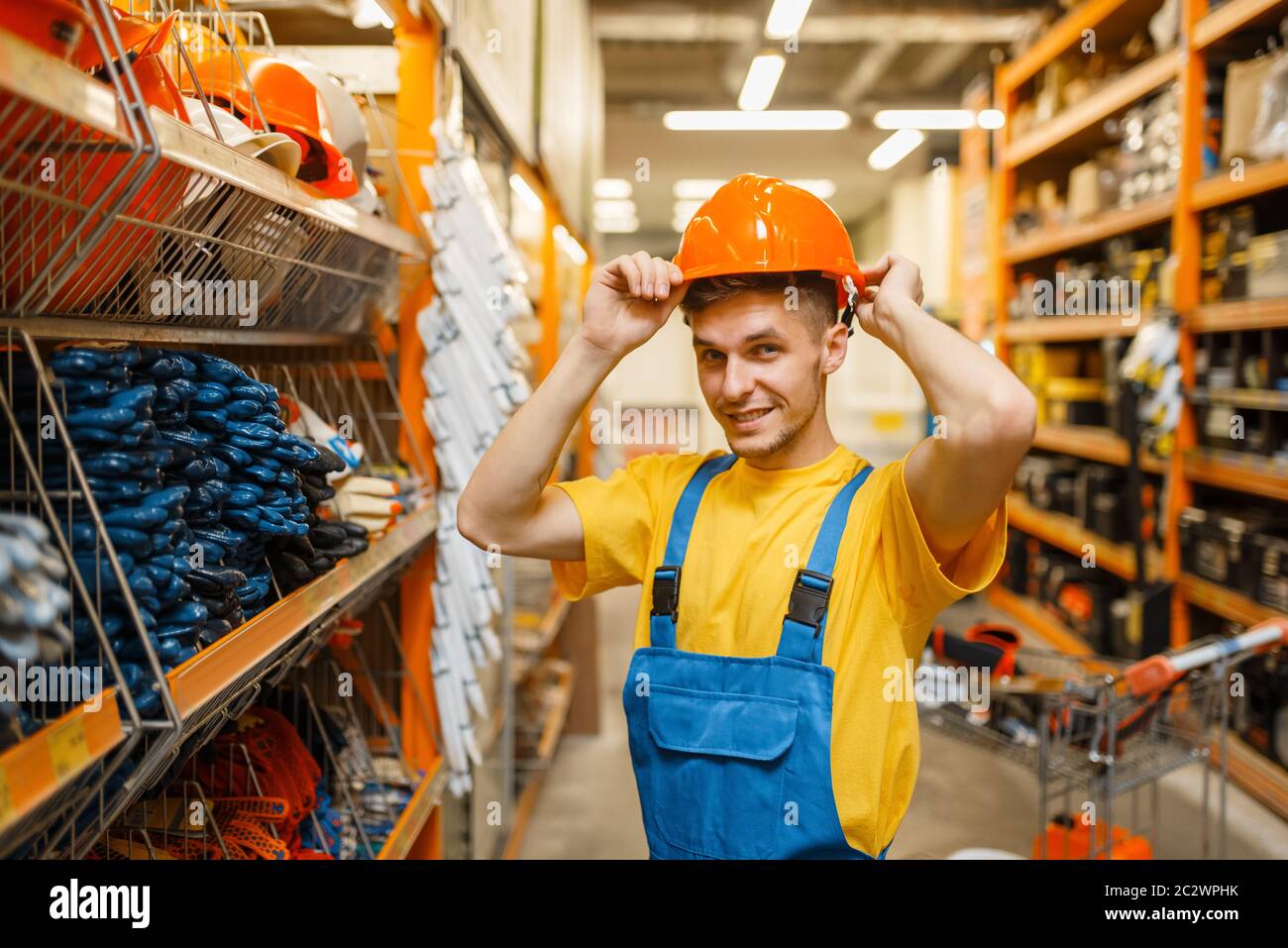Male builder trying on helmet at the shelf in hardware store ...