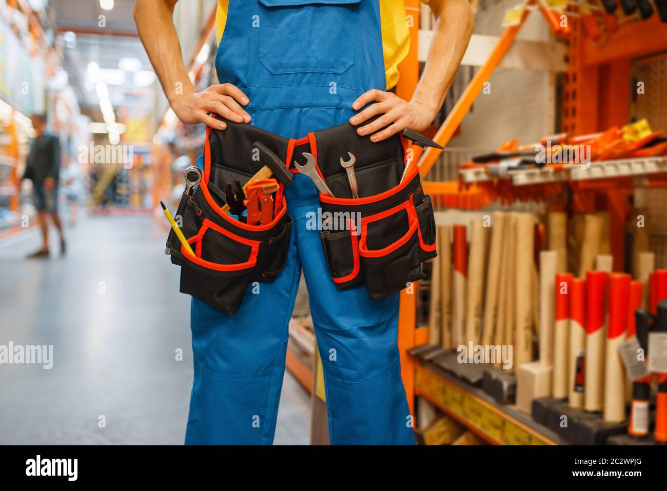 Male builder trying on tool belt at the shelf in hardware store ...