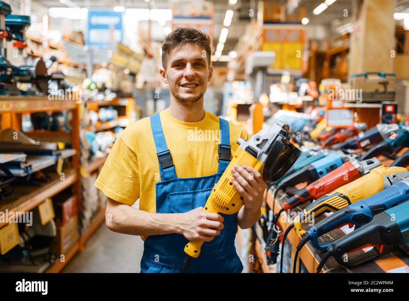 Male builder choosing angle grinder at the shelf in hardware store ...
