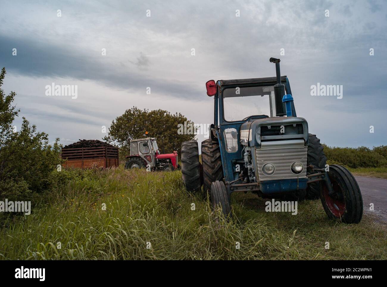 Old tractors and trailers collecting peat bog for fuel in rual Ireland ...