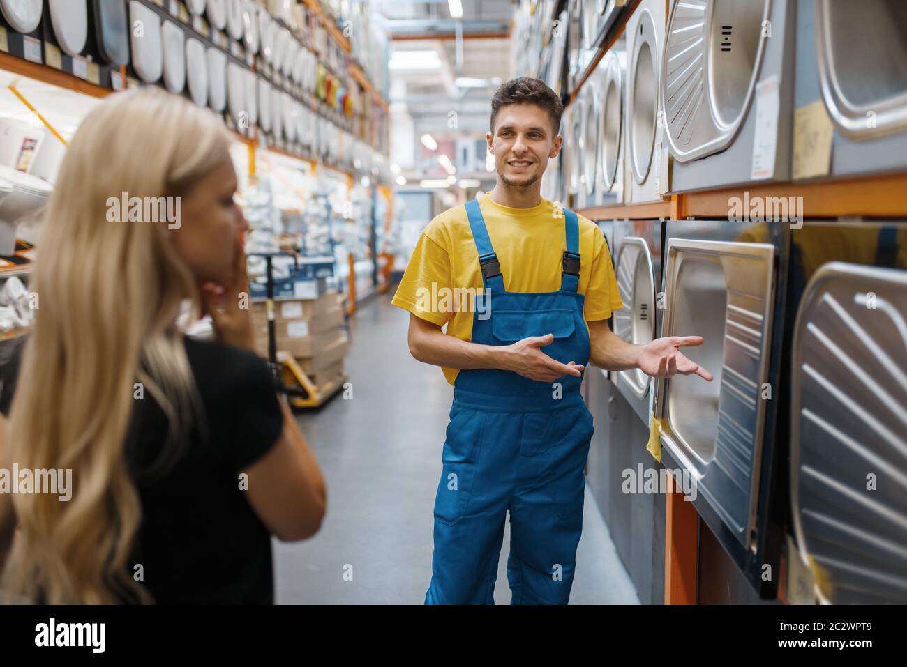 Assistant and female buyer in hardware store. Seller in uniform and ...