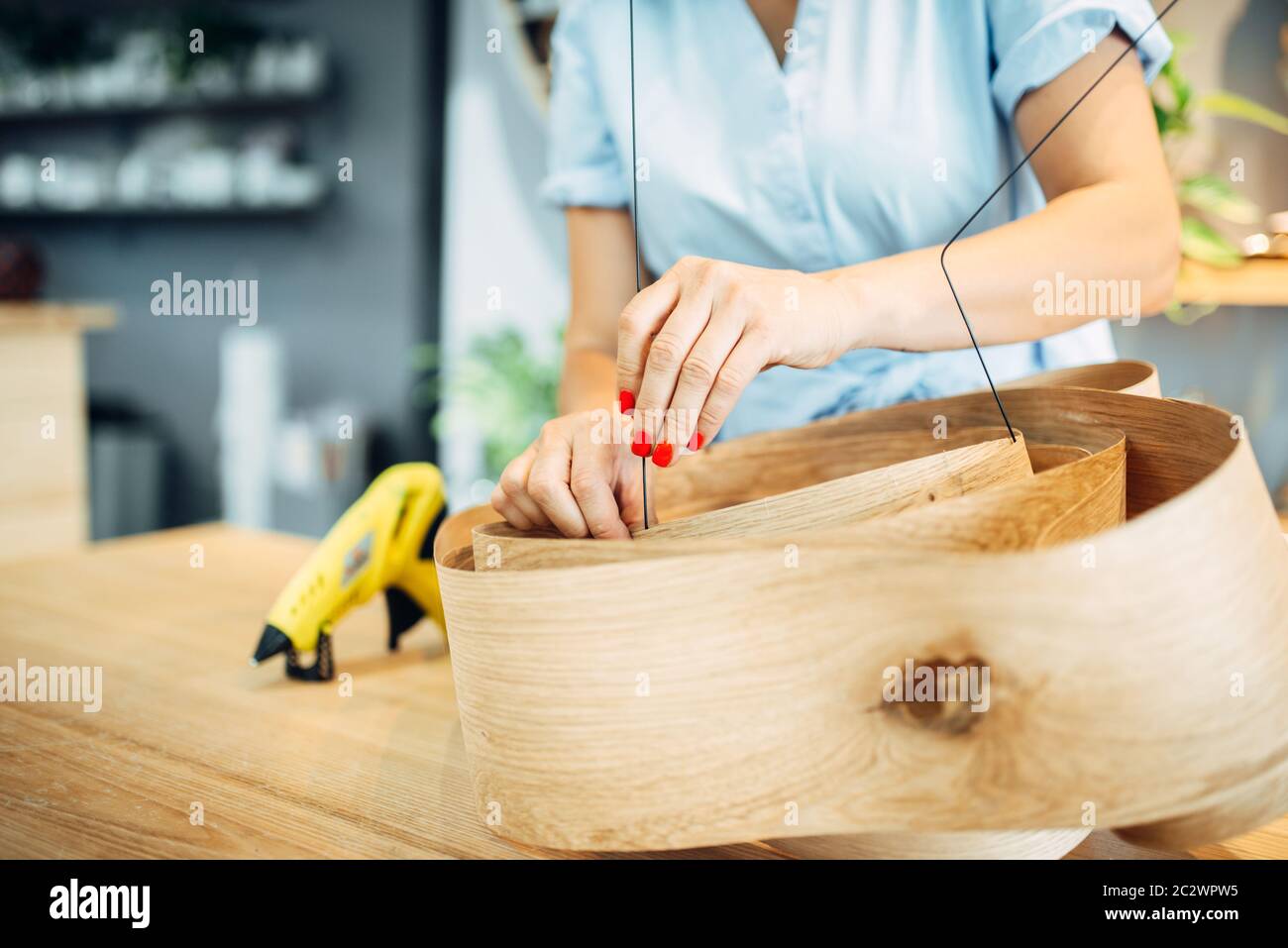 Female florist works with glue gun in flower shop. Wrapping decoration ...