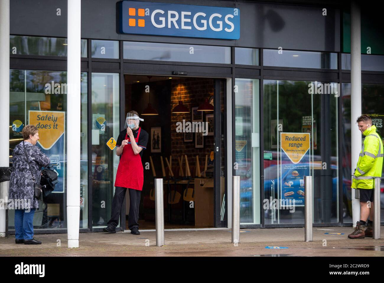 Cardiff, Wales, UK. 18th June, 2020. A shop worker wearing PPE speaks ...