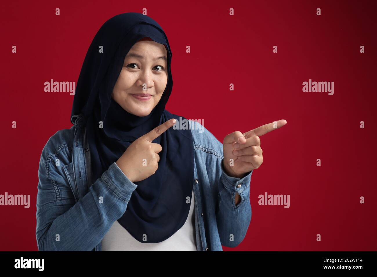 Portrait of Asian young happy muslim woman pointing to presenting ...