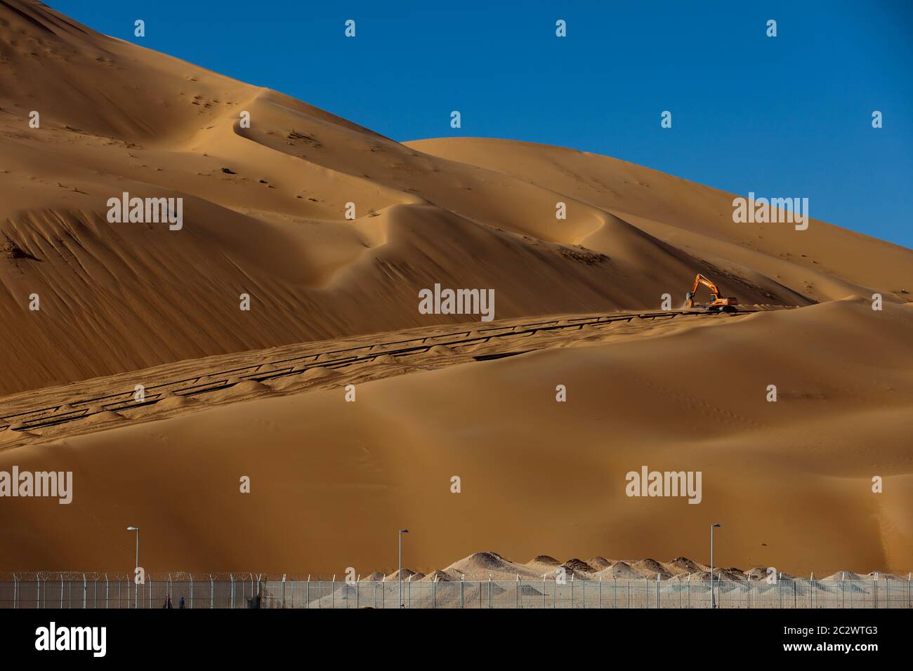 An excavator, piles on sand to bury a new export pipline in the Sahara ...