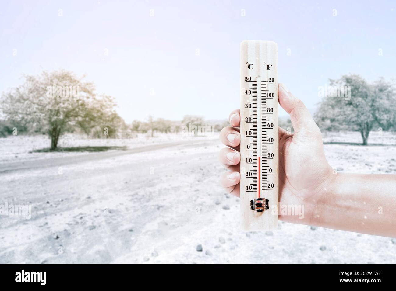 Hand holding thermometer measuring the temperature outdoor with a clear ...