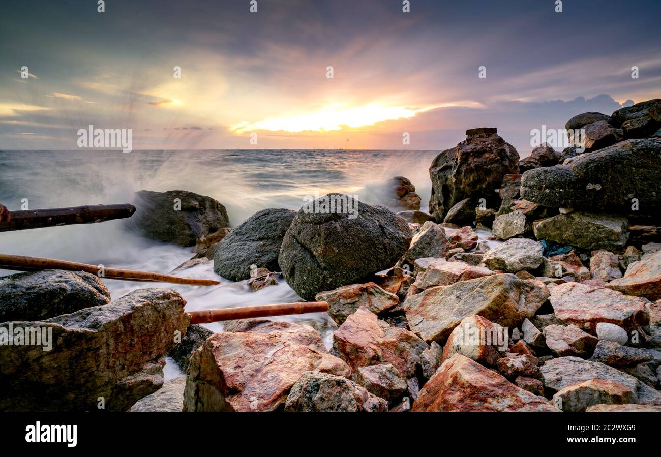 Ocean water splash on rock beach with beautiful sunset sky and clouds ...