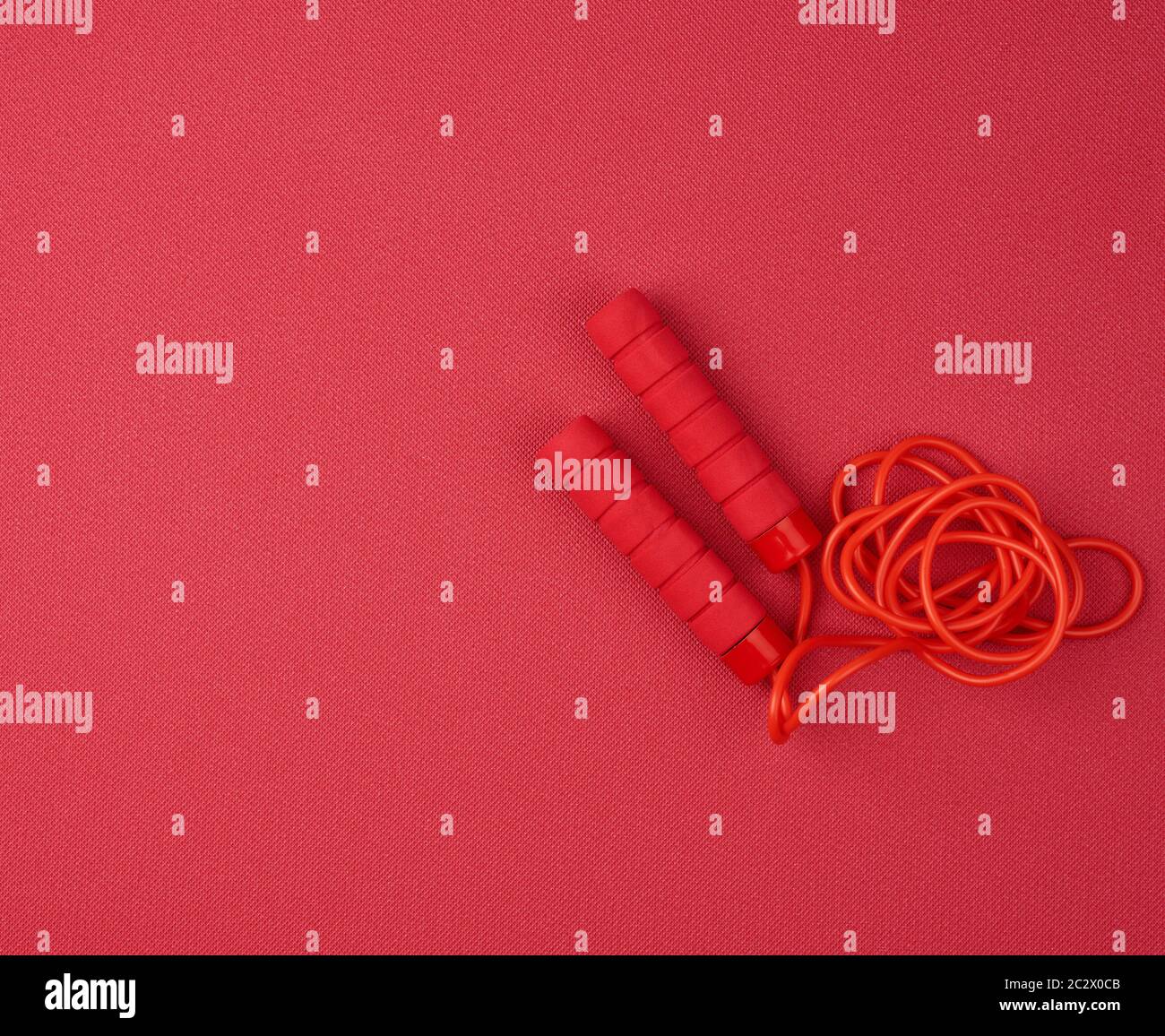 red jump rope lies on a neoprene red sports mat, close up, copy space ...