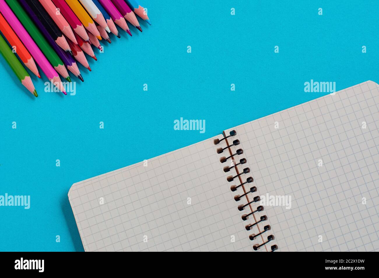 Colored pencils and notebook on a blue background. Copy space Stock ...