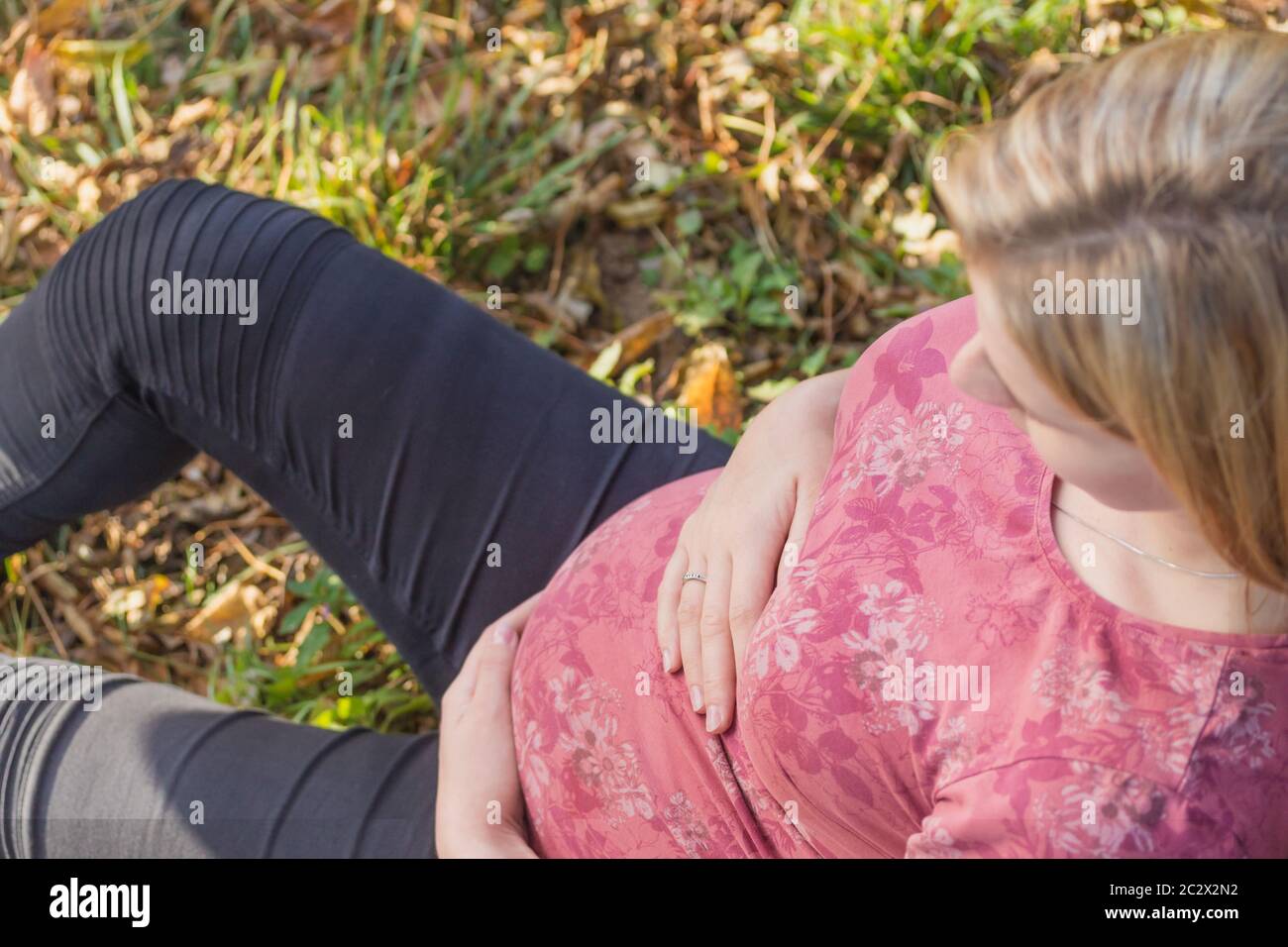 Top view of young pregnant woman sitting and holding her belly ...