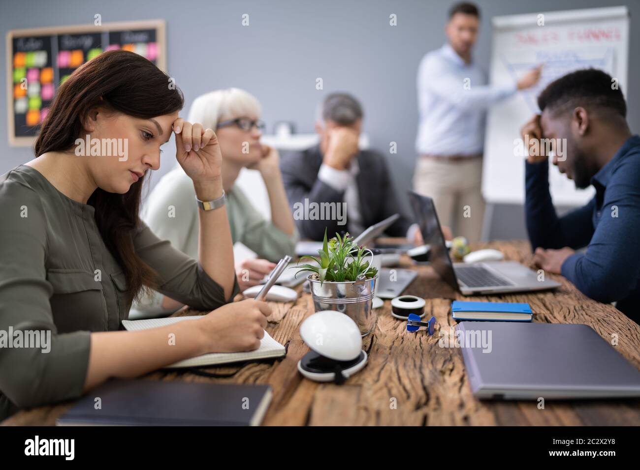 Upset Businesspeople Sitting In Office While Their Colleague Giving ...