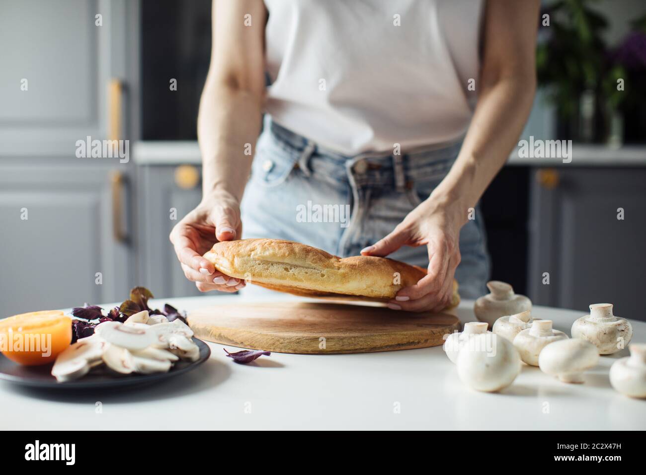 Girl breaks bread with her hands in the bright kitchen. Healthy food ...