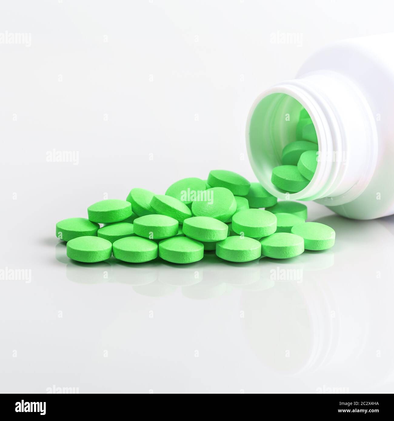 Green pills are scattered from a jar on a white background Stock Photo ...