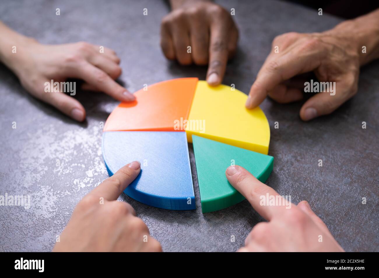 Businesspeople Connecting Pieces Of Multi Colored Pie Chart On Desk ...