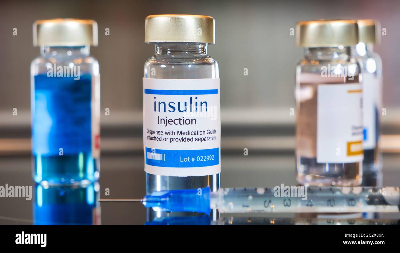 Bottle of Insulin injection with a syringe on black table and stainless ...