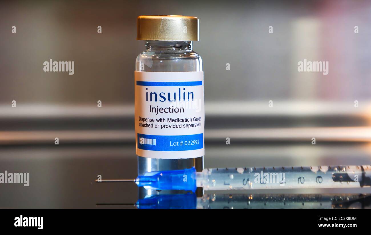 Bottle of Insulin injection with a syringe on black table and stainless ...