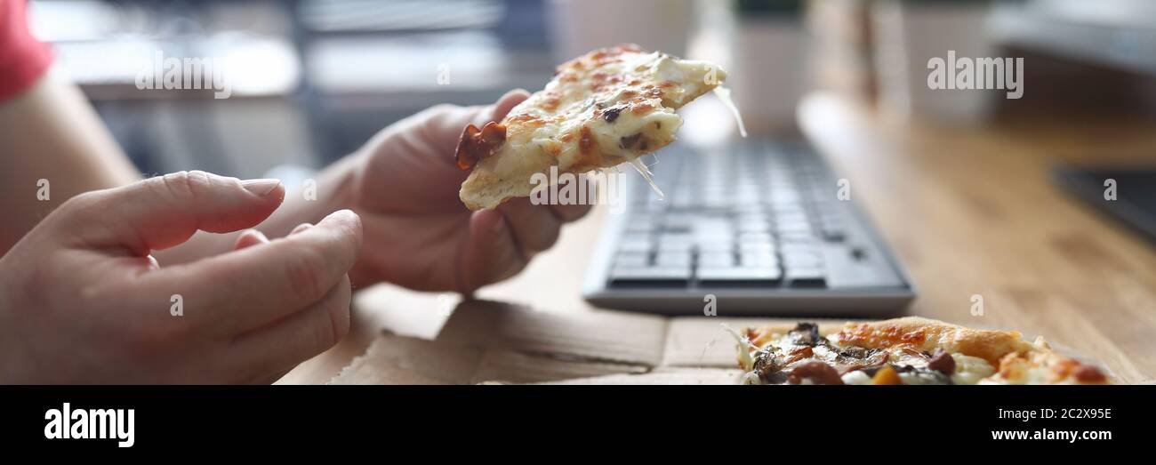 Man eating pizza in workplace in front computer Stock Photo - Alamy