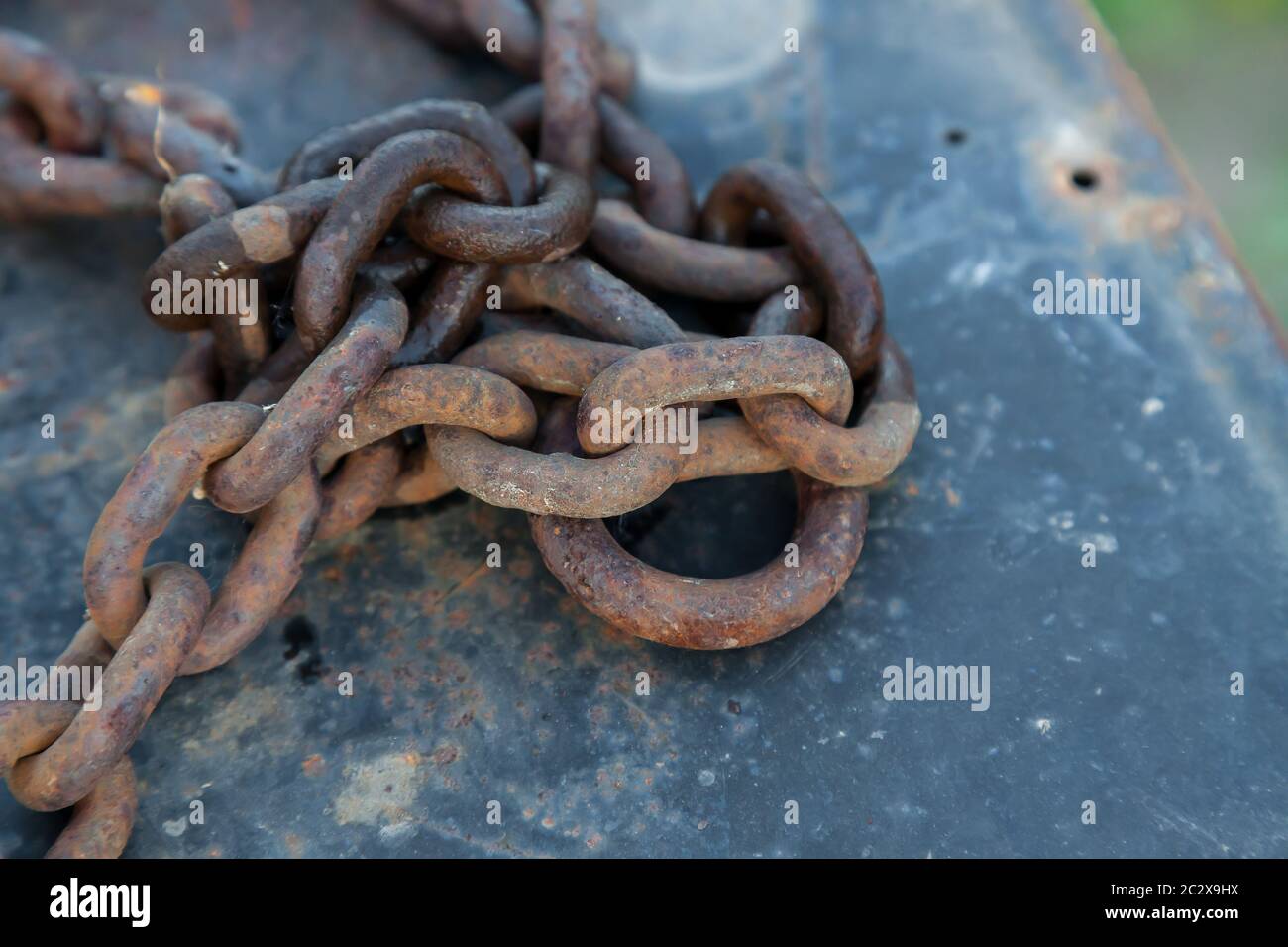 Forged old metal chain on the pier moored boat with peeling blue paint ...