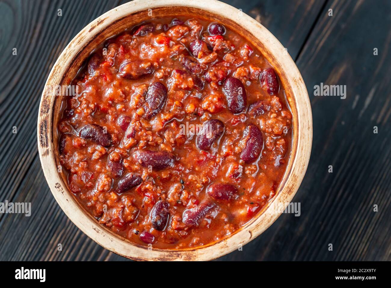 Bowl of chili con carne on a wooden table: top view Stock Photo - Alamy