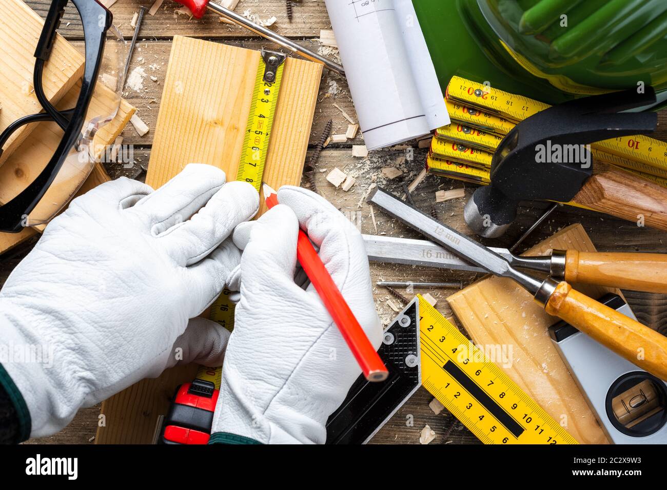 View from above. Carpenter wears protective leather gloves, with pencil ...