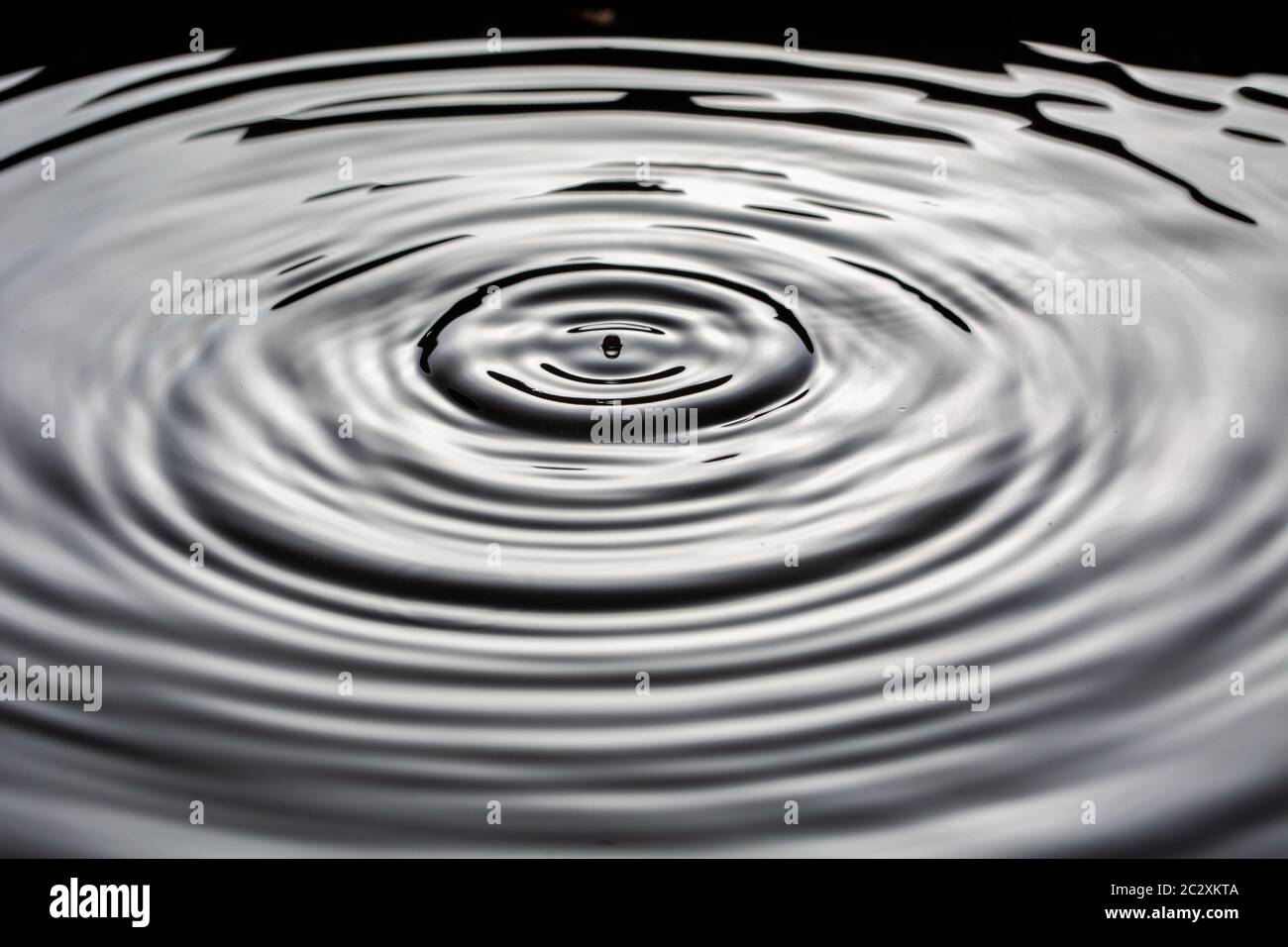 Drops of rain splashing into a puddle, water splashing making circular ...