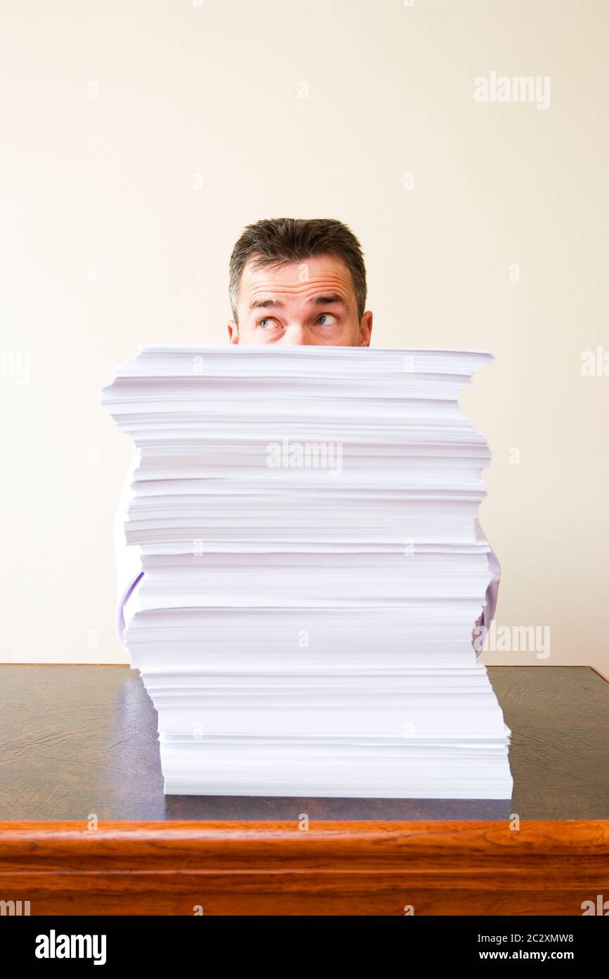 Businessman behind a stack of paper Stock Photo - Alamy