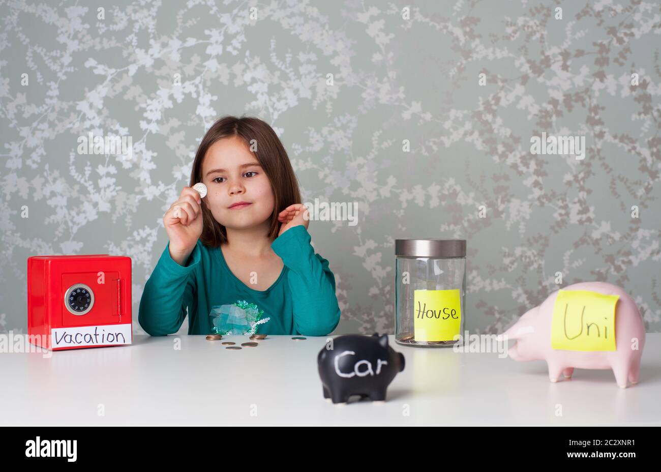 Girl holding a coin surround by piggy banks and money boxes Stock Photo ...