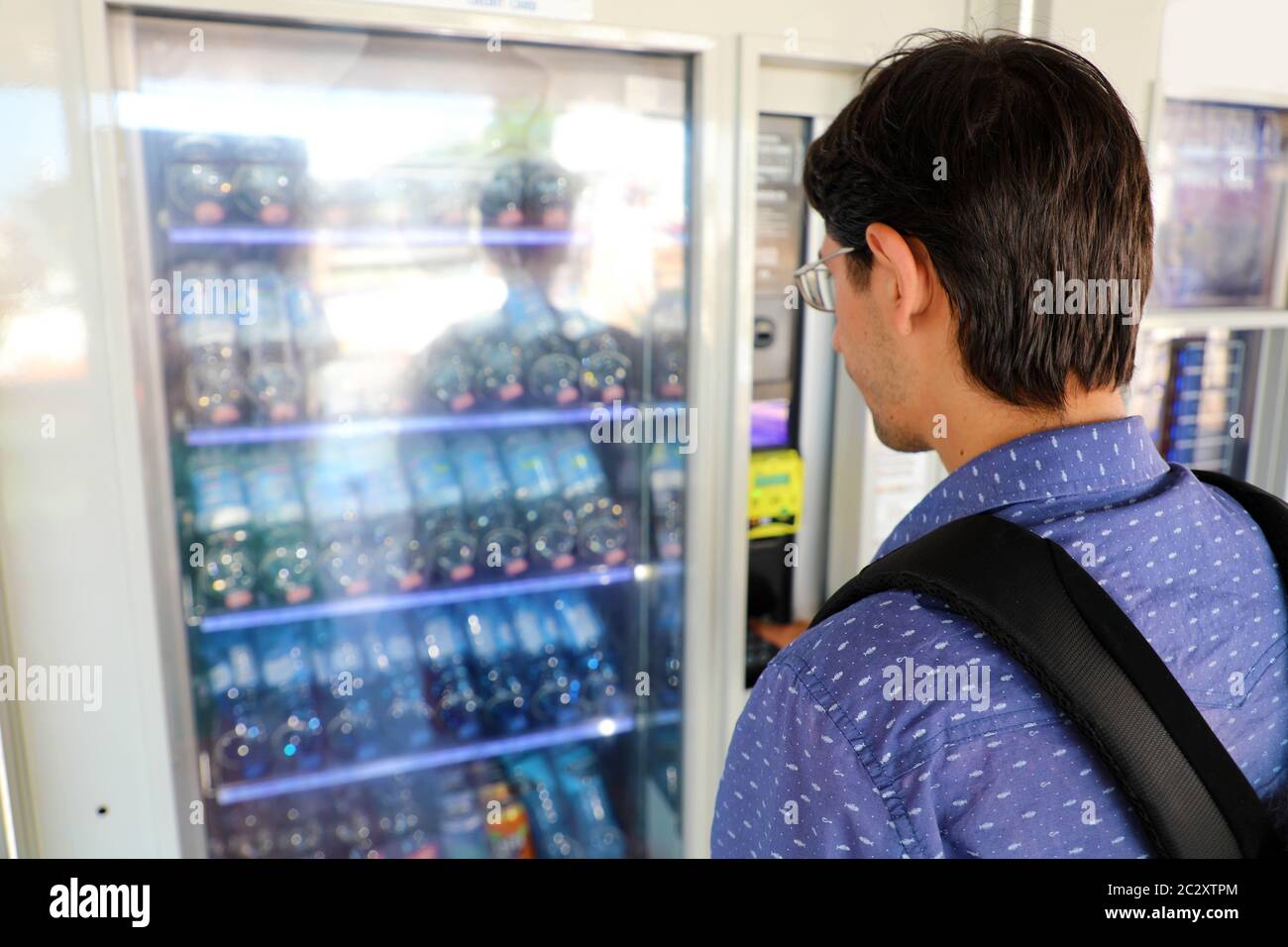 Young male backpacker tourist choosing a snack or drink at vending ...