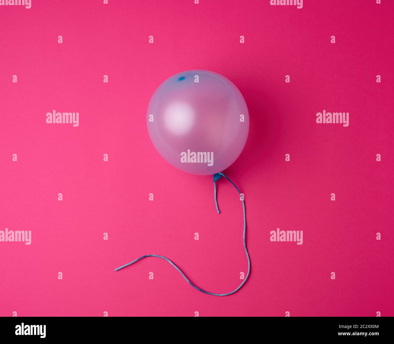 inflated blue rubber balloon on a pink background, blue rope Stock ...