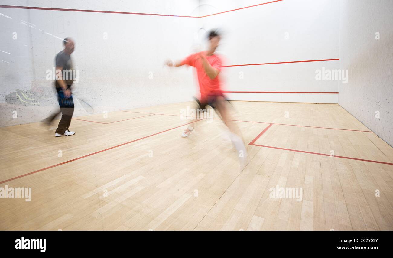Squash players in action on a squash court (motion blurred image; color ...