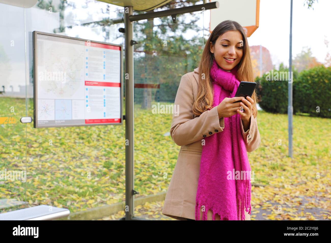 Young woman messaging with mobile phone waiting bus on bus stop Stock ...