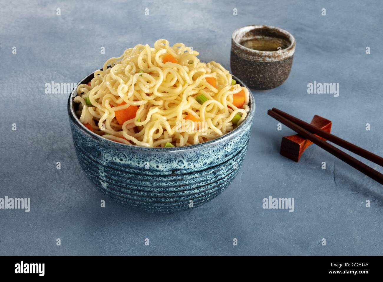 Instant noodles with carrot and scallions, with sake and chopsticks, a ...