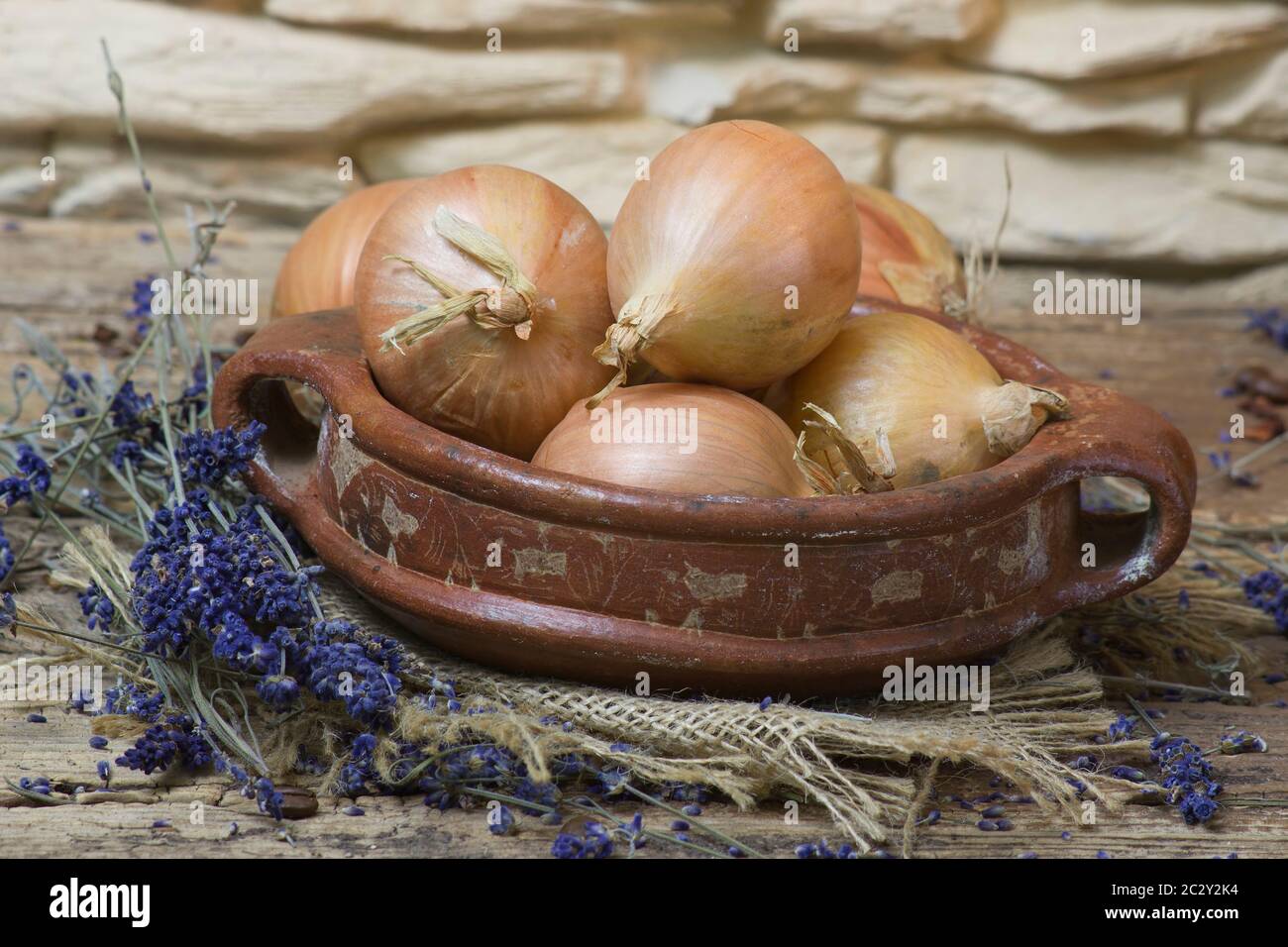 fresh onions in a clay pot and lavender flowers - wooden background ...
