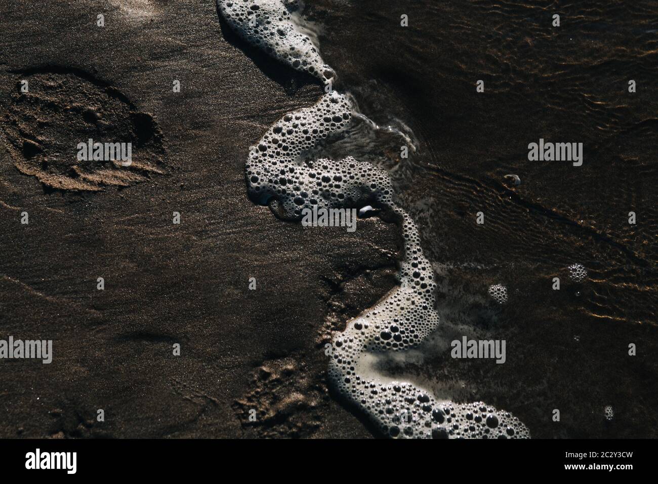 Sea foam from a wave on a beach in devon with dark sand Stock Photo - Alamy
