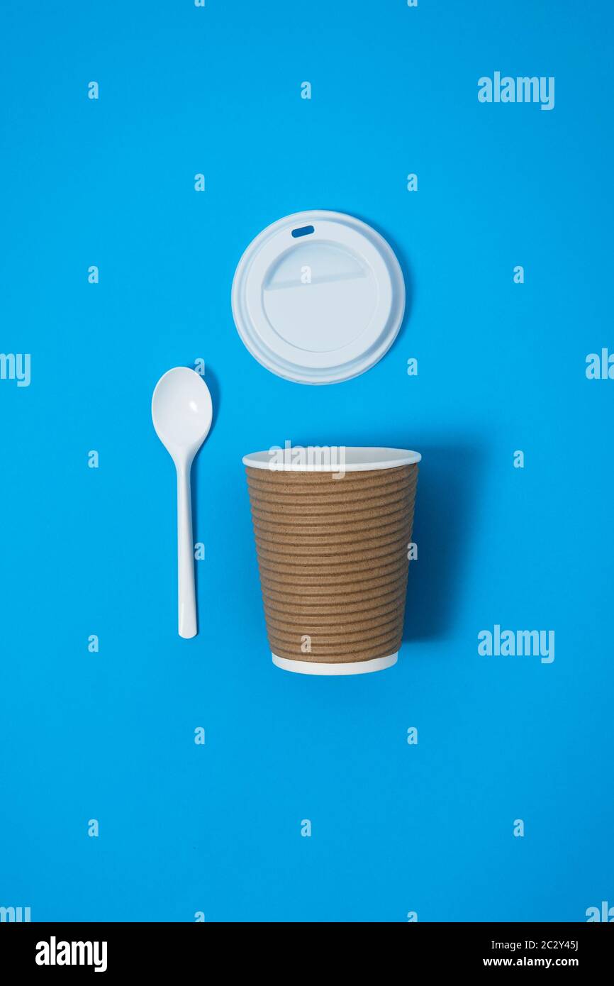 reusable cup with plastic cap and spoon on a plain blue background ...
