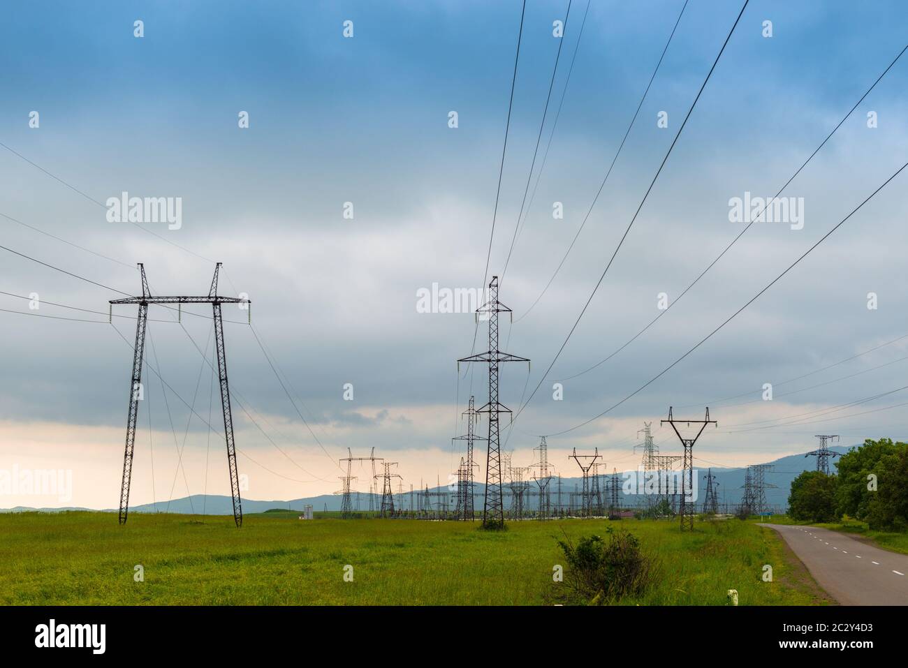 Power lines in a green field and dark blue clouds Stock Photo - Alamy