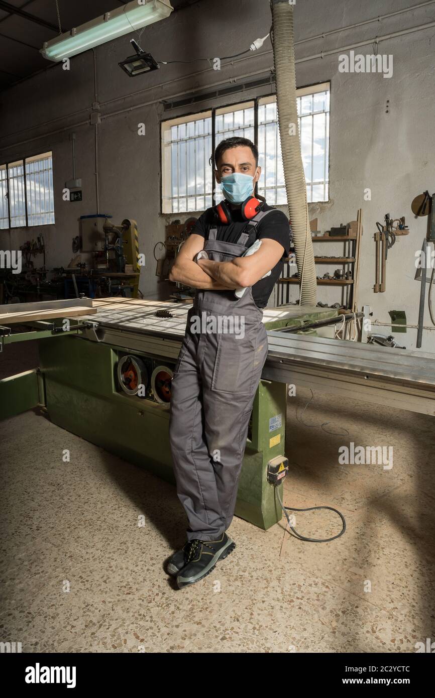 Worker standing wearing mask and protective gear looking at camera in a ...