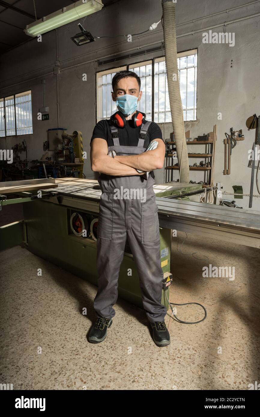 Worker standing wearing mask and protective gear looking at camera in a ...