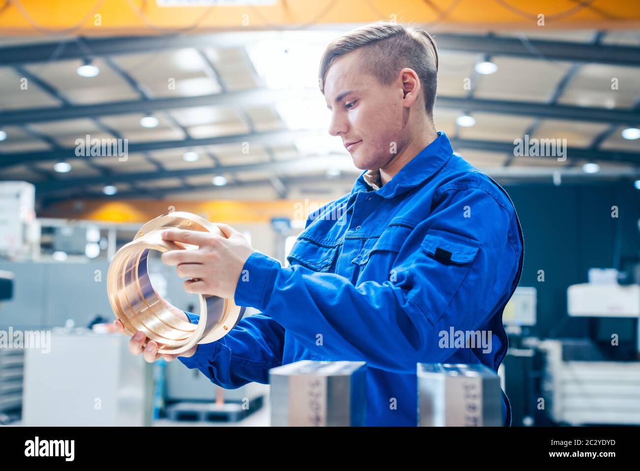 Apprentice in metalworking looking at workpiece being satisfied Stock ...