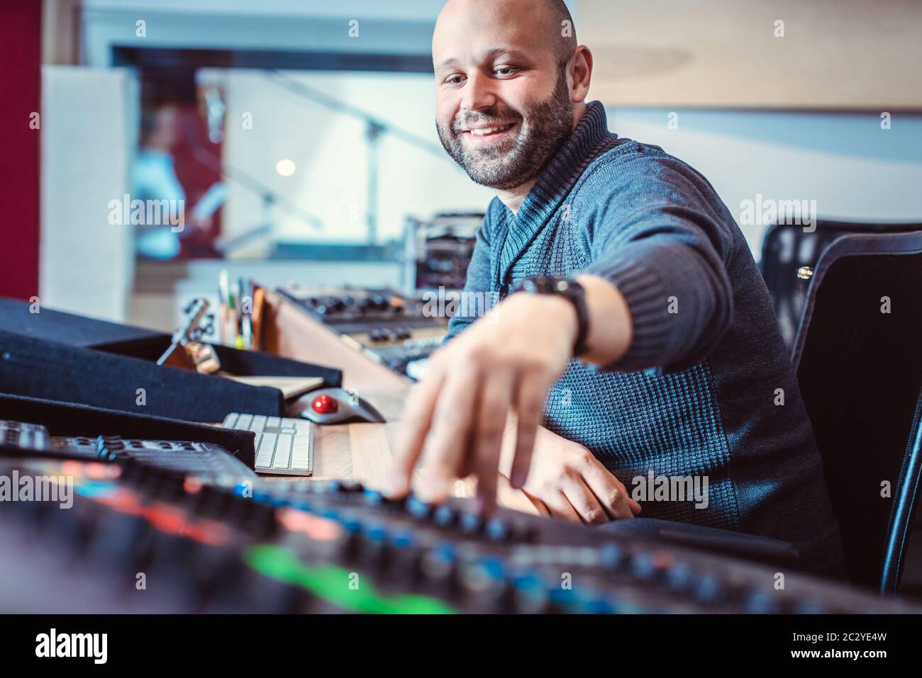 Sound engineer mixing a song in his studio pushing a fader and the ...