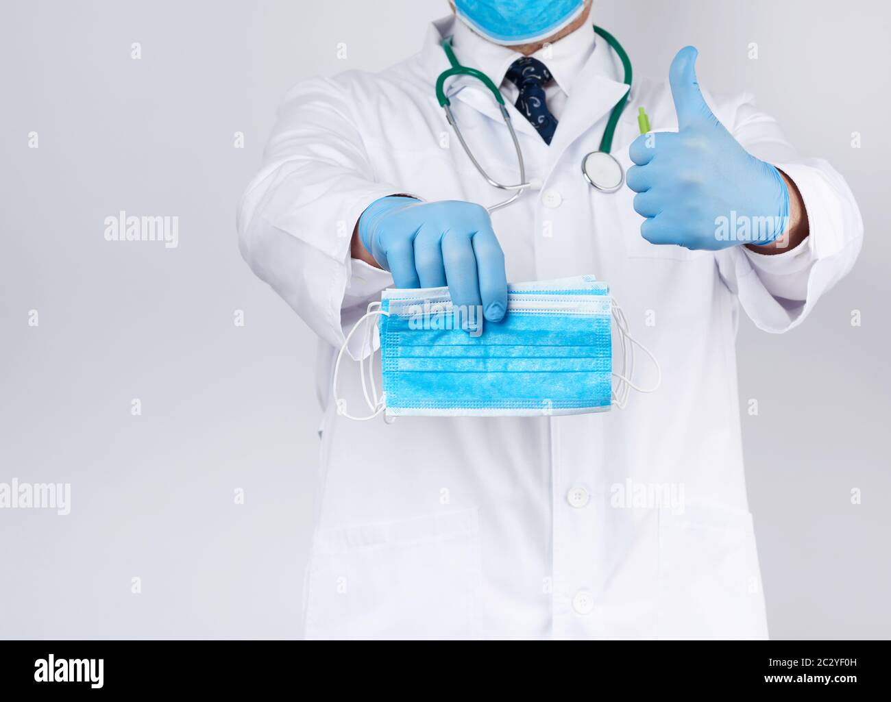 doctor in a white coat, blue latex sterile gloves holds textile medical ...